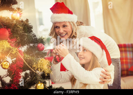 Happy mother with cute daughter decorating Christmas tree at home Stock ...