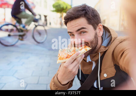 Handsome man eating tasty pizza at home Stock Photo - Alamy