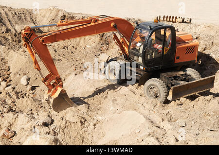 Wheel loader excavating an excavation pit with a sheet pile wall Stock ...