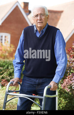 Elderly man with a Zimmer frame walking with the aid of a healthcare ...