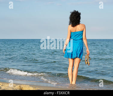 Brunette woman standing over blue background looking surprised and ...