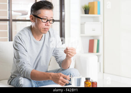 Asian man holding thermometer and water with pills for sickness Stock ...