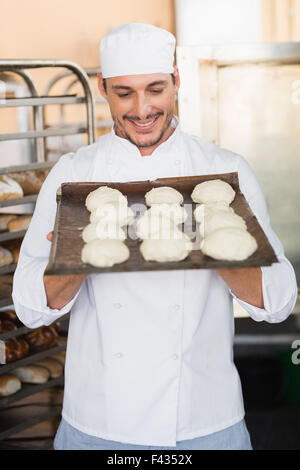 Smiling baker holding tray of raw dough Stock Photo - Alamy