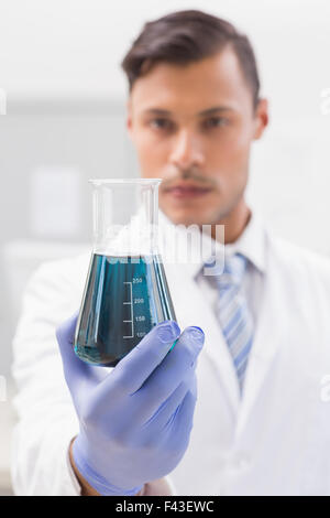 Concentrated scientist looking at beaker Stock Photo - Alamy