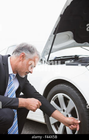 Businessman checking tire Stock Photo - Alamy