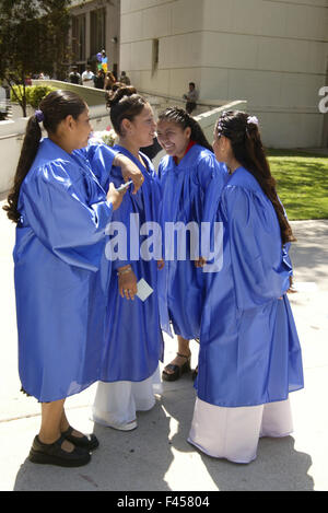 Hispanic middle school girls wearing blue graduation gowns await ...