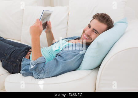 Happy man using tablet computer while sitting on sofa at home Stock ...