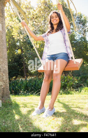 Pretty brunette swinging in park Stock Photo - Alamy