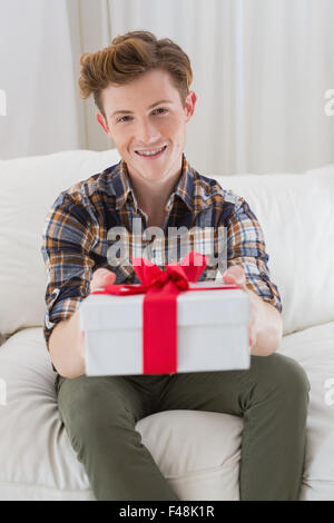 Young handsome man holding gift smiling with an idea or question ...