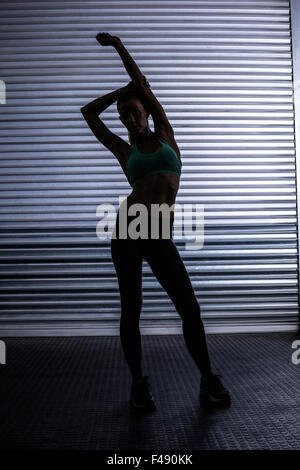 Muscular woman stretching in shadow room Stock Photo - Alamy