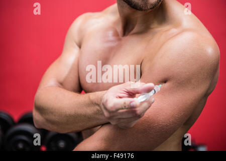 Muscle man injecting steroids into his strong arm using a syringe Stock ...