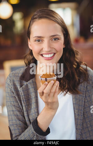 Smiling young woman showing muffin Stock Photo - Alamy