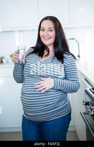 A beautiful pregnant Caucasian woman drinking tea while sitting on a ...