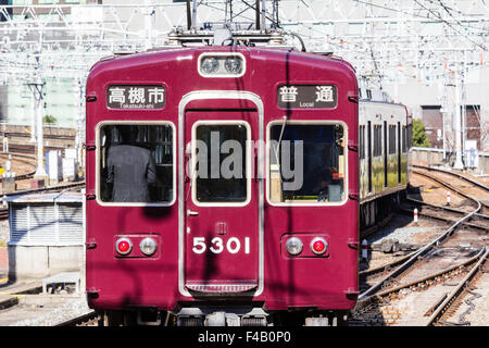 Japan, Osaka, Umeda. Private Hankyu railway, Maroon coloured train with ...