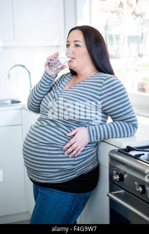 A beautiful pregnant Caucasian woman drinking tea while sitting on a ...
