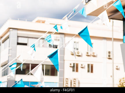 White triangular flags waving in wind blue sky background close up ...