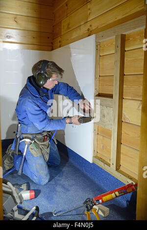 A builder staples off waterproof wall cladding in a bathroom Stock ...