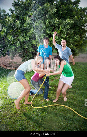 Five friends splashing with water in the garden Stock Photo - Alamy