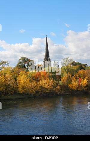View of cathedral spire and belltower sticking up above Autumn foliage ...