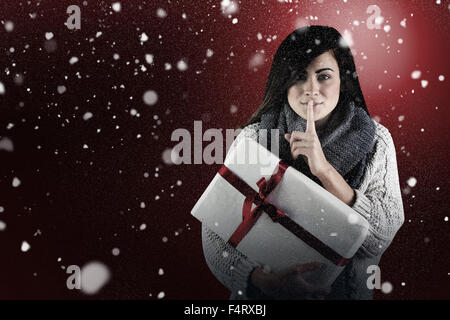 Composite image of festive brunette keeping a secret Stock Photo - Alamy