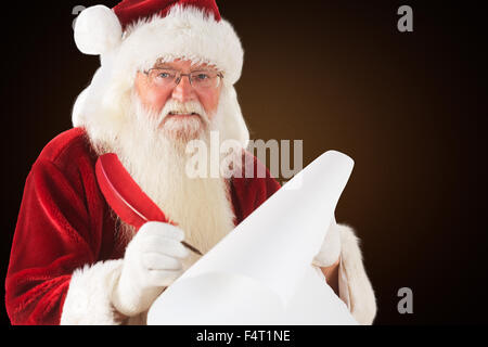 Composite image of santa claus writing on scroll Stock Photo - Alamy