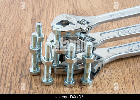 Stack of three adjustable wrenches with upright nuts and bolts in front ...