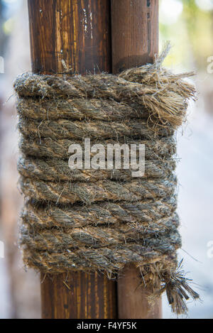 old rope wrapped around a pole that is surrounded by sand, beach Stock ...