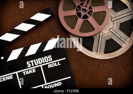 Movie clapper board detail and colored film reels on brown table Stock ...