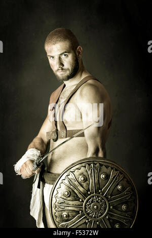 Gladiator posing with shield and sword in a dark background Stock Photo ...
