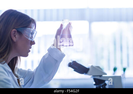 Scientist holding up beaker of chemical Stock Photo - Alamy