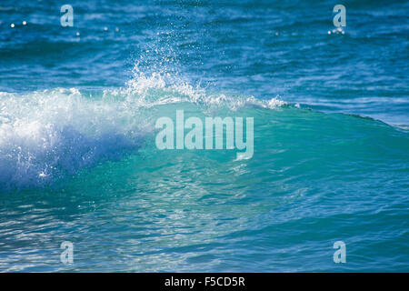 backlit ocean waves breaking by the shores of Gran Canaria, two bathers ...