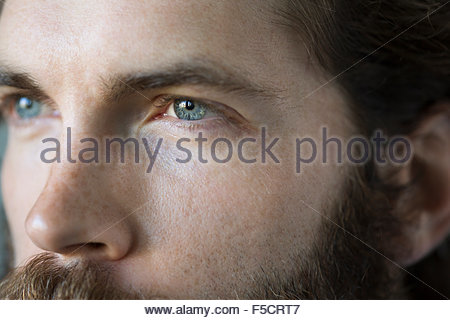 Handsome man with blue eyes and beard wearing denim jacket looking ...