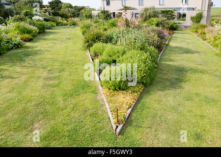 Triangular raised flower bed on large garden lawn Stock Photo - Alamy
