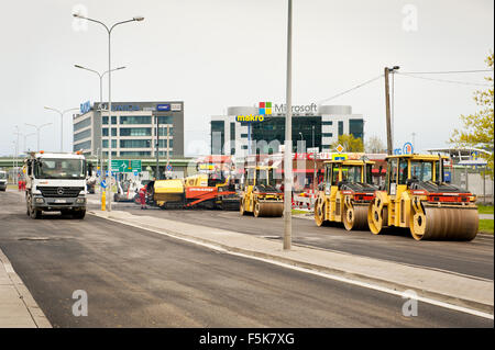 Asphalt paver and road roller machines on a construction site in a park ...