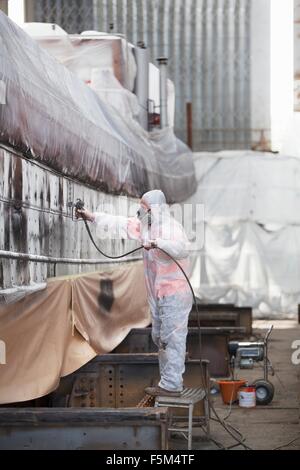 Worker spray painting boat in shipyard Stock Photo - Alamy