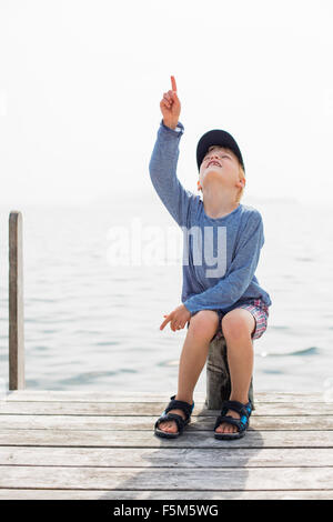 Boy sitting on the jetty at a lake Stock Photo - Alamy