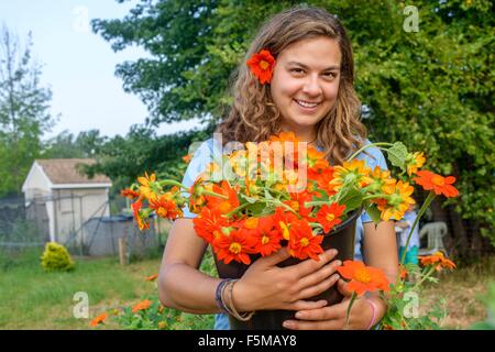 Smiling farm worker holding bucket with harvested plums in garden Stock ...