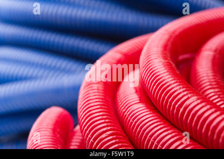 Rolls of red and blue water pipes Stock Photo - Alamy
