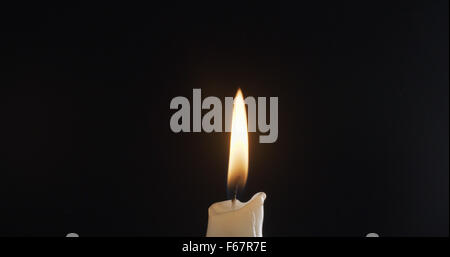single thin candle with fire on dark Stock Photo - Alamy