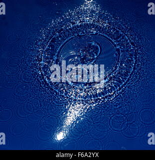 Circles and splash on water from raindrops on background an old fence ...