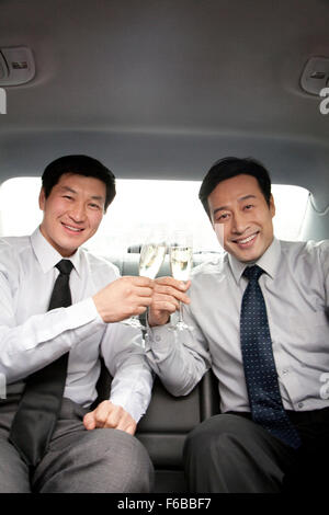 Businessmen toasting in back of car Stock Photo - Alamy
