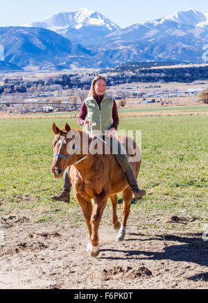 Attractive woman riding horse bareback in ranch pasture with Rocky ...
