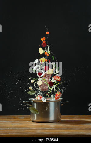 vegetable meat ingredients falling into stainless steel cooking pot ...