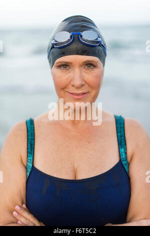 female swimmer standing on the beach doing stretching exercises Stock ...