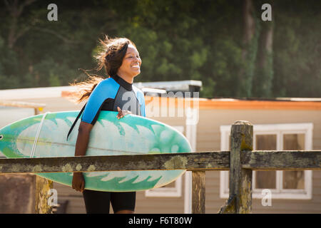 Woman carrying surfboard outdoors Stock Photo - Alamy