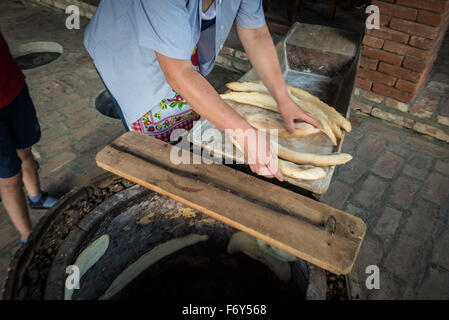 Woman shows traditional way of Shoti Bread baking in oven called tone ...