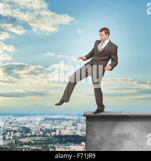 Businessman stepping from edge of building roof Stock Photo - Alamy