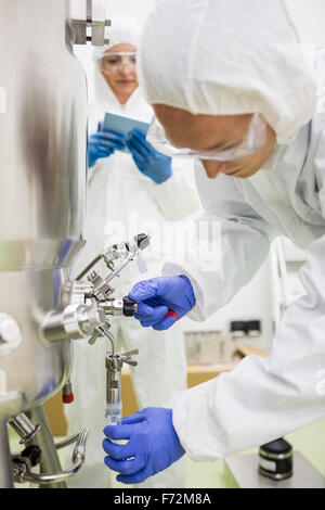 Scientists working with large vat Stock Photo - Alamy