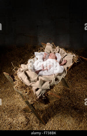 Manger with baby Jesus and hay on snow against dark background Stock ...