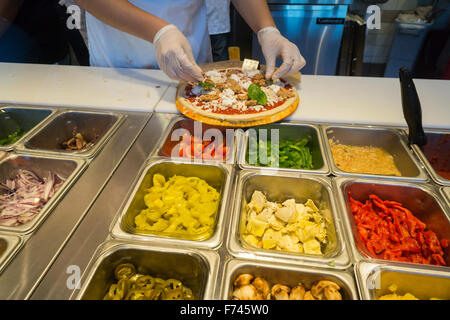 Employees construct a pizza right before the customers' eyes in ...